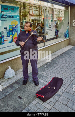 A street busker playing his violin in the streets of Whitby on the east ...