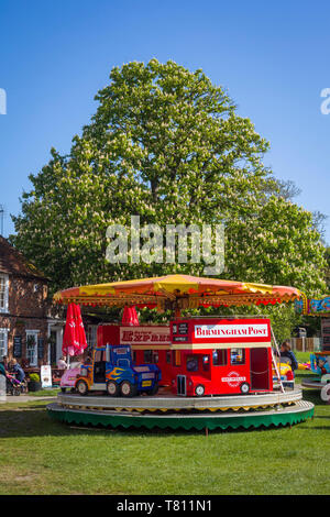 A colourful Fairground roundabout with a horse Chestnut tree behind on ...