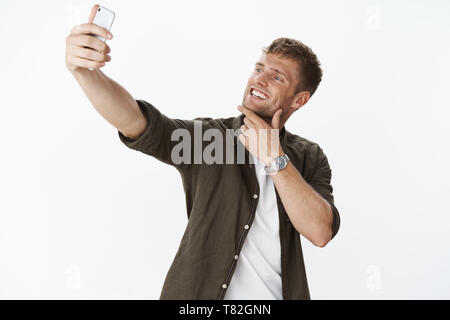 Happy man smiling broadly, extending his arm to take a selfie in a ...