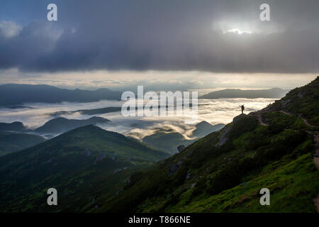 Wide mountain panorama. Small silhouette of tourist with backpack on ...