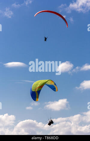 Two people tandem skydiving with a parachute from below backlit against ...