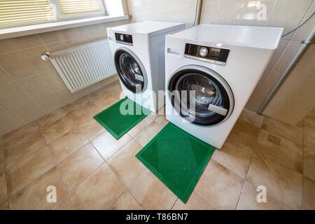 Modern new industrial washing machines on rubber insulation mats in ...
