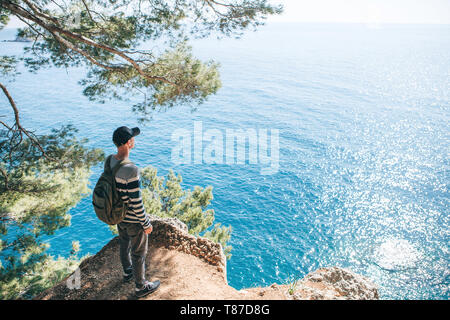 A traveler with a backpack on at viewpoint looks through binoculars at ...