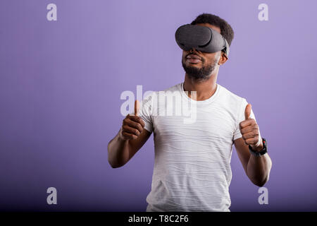 Dark skinned young man experiencing virtual reality showing thumb up playing video games using oculus rift headset. 3d technology innovation enter Stock Photo Alamy
