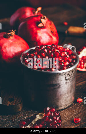 Metal mug full of pomegranate seeds. Whole fruits and pomegranate ...