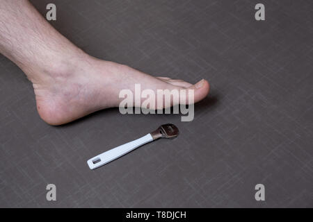 Man removing corn, callus from his feet using a razor file, masculine ...