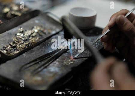 Goldsmith working and soldering an unfinished jewelry piece with a ...