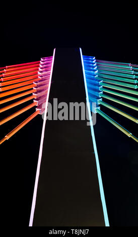 Abstract closeup of multi coloured lit cables attaching to a pylon ...