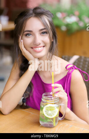 Young woman drinking fresh lemonade while sitting on window sill Stock ...