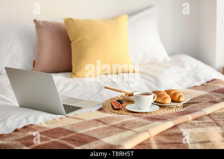 Wicker mat with delicious breakfast and laptop on bed Stock Photo - Alamy