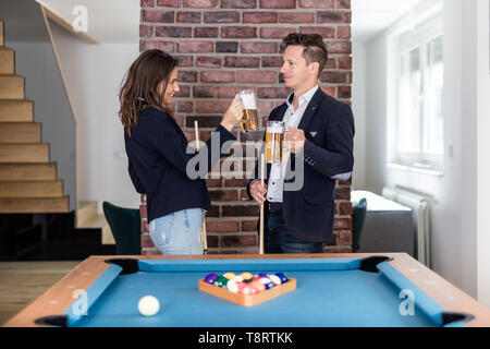 Couple cheering with beer next to billiard pool table Stock Photo - Alamy