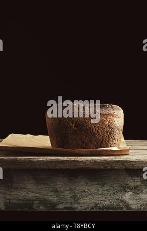 baked rye bread lies flour on a textile towel, wooden old table, black ...