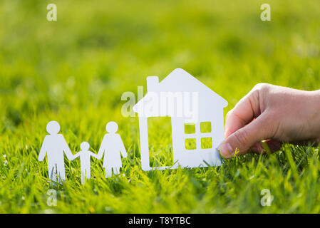 Cutout paper family and house on green grass and bright blurred ...