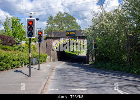 Low arch bridge with warning sign and high visibility markings, with ...