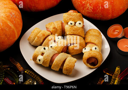 Scary sausage mummies in dough with funny eyes on table. Halloween food ...
