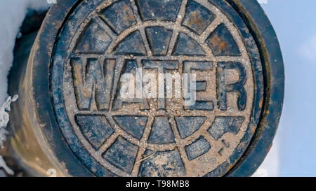 Close up view of a dirty metal water pipe buried in frosty white snow ...