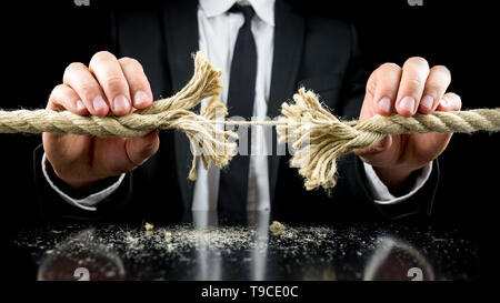 Man holding a frayed rope with one remaining string intact in both his ...