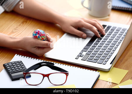 Woman squeezing stress ball while working with laptop Stock Photo - Alamy