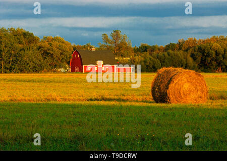 Canada, Manitoba, Matlock. Red barn and bale at sunrise. Credit as ...