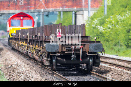 Freight train pulling empty trailers for carrying steel rail tracks ...