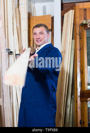 workman standing with long wooden plank in workshop Stock Photo - Alamy