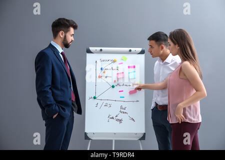 Team of young people near grey wall in office Stock Photo - Alamy
