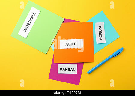 Paper stickers with words AGILE, SCRUM, KANBAN on color background ...