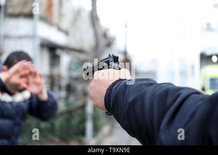 Armed bandit aiming at helpless victim outdoors Stock Photo - Alamy