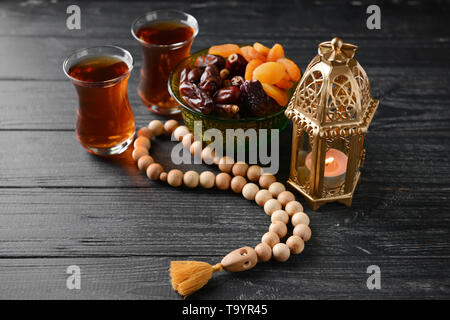 Muslim lamp, dried fruits, tea and tasbih on wooden table Stock Photo ...