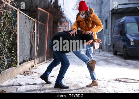Young woman defending herself from attack by thief on color background ...
