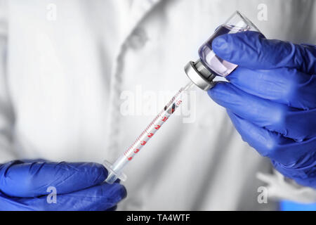 Doctor drawing up medicine into a syringe in a medical treatment room ...
