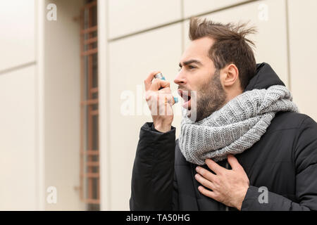 Young man with inhaler having asthma attack on color background Stock ...