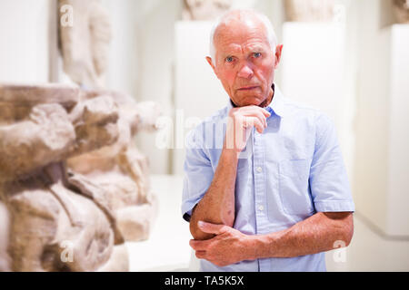 Attentive mature man observing sculptures exhibition in art museum ...