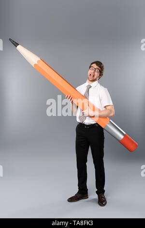 funny businessman in glasses holding huge and heavy decorative pencil ...