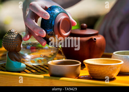 On the table on a wooden tray a teapot with tea, teapot, cups. Man ...