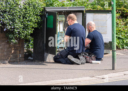 Two telecoms engineers working in a junction box. Telecom ...