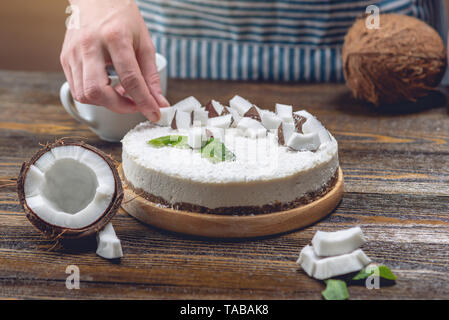 Confectioner decorates coconut raw cake with white pulp and mint on ...