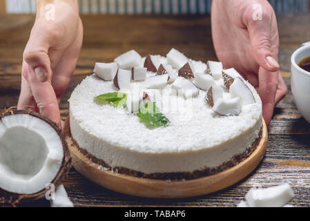 Confectioner decorates coconut raw cake with white pulp and mint on ...