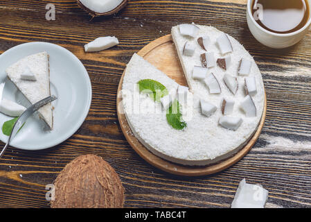 Raw coconut cake decorated with white pulp and mint on a blue wooden ...