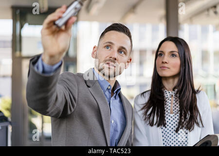 Businessman and businesswoman examining workpiece in factory Stock ...