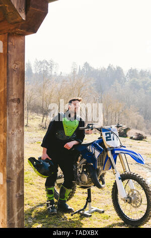 Motocross driver with jacked up motorbike Stock Photo - Alamy
