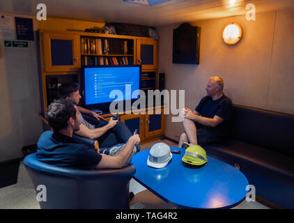 Happy team of ship officers watch TV onboard of vessel Stock Photo - Alamy