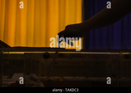 Silhouette of a hand casting a vote at a polling station during the ...