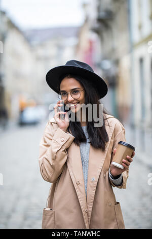 Happy urban girl drinks her takeaway coffee and scrolls feed on ...