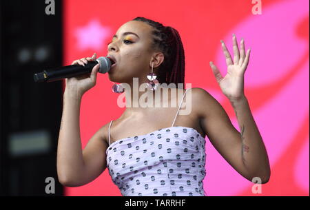 Singer Ravyn Lenae is shown performing on stage during a live concert ...