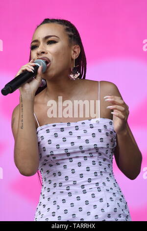 Singer Ravyn Lenae is shown performing on stage during a live concert ...