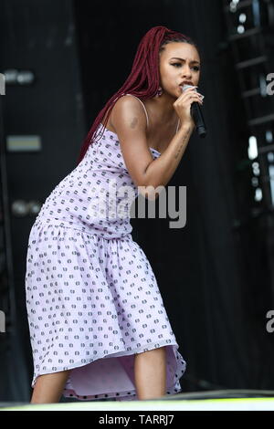 Singer Ravyn Lenae is shown performing on stage during a live concert ...