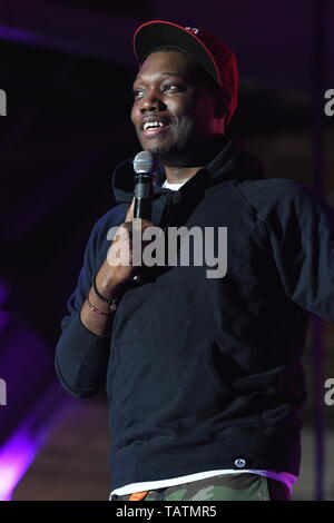 Comedian Michael Che is shown performing on stage during a "live" stand ...