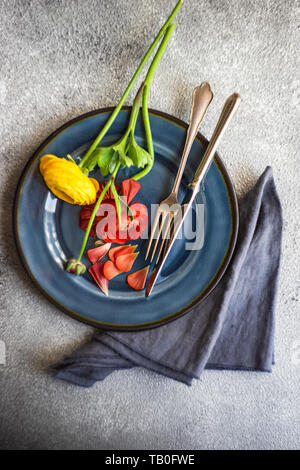 Rustic table setting with ranunculus flowers on concrete background ...