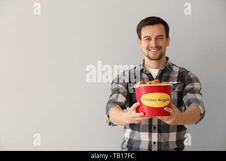 Handsome man with bucket of tasty nuggets on color background Stock ...